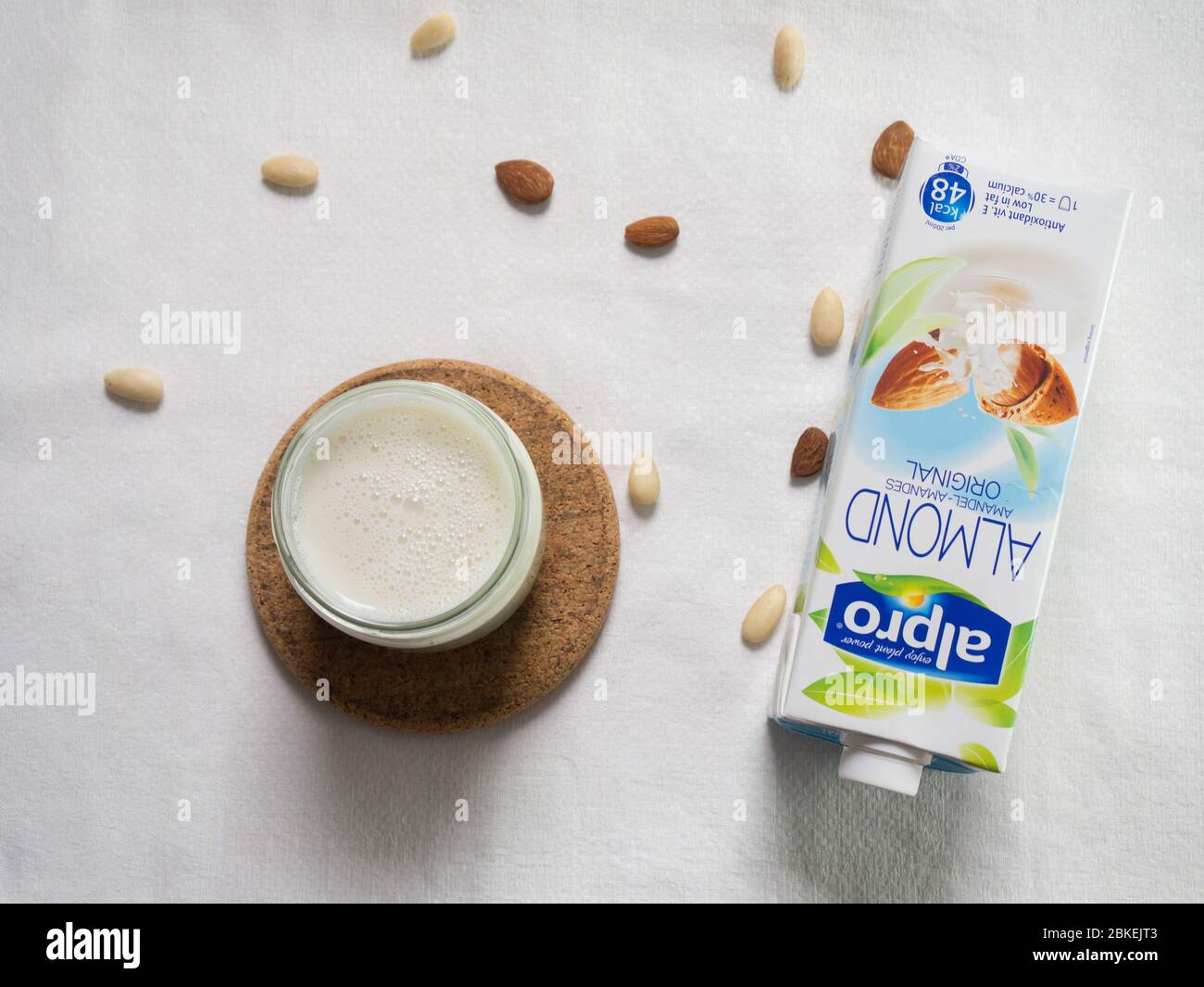 Staging of a brick of Alpro vegetable milk next to a glass of almond ...
