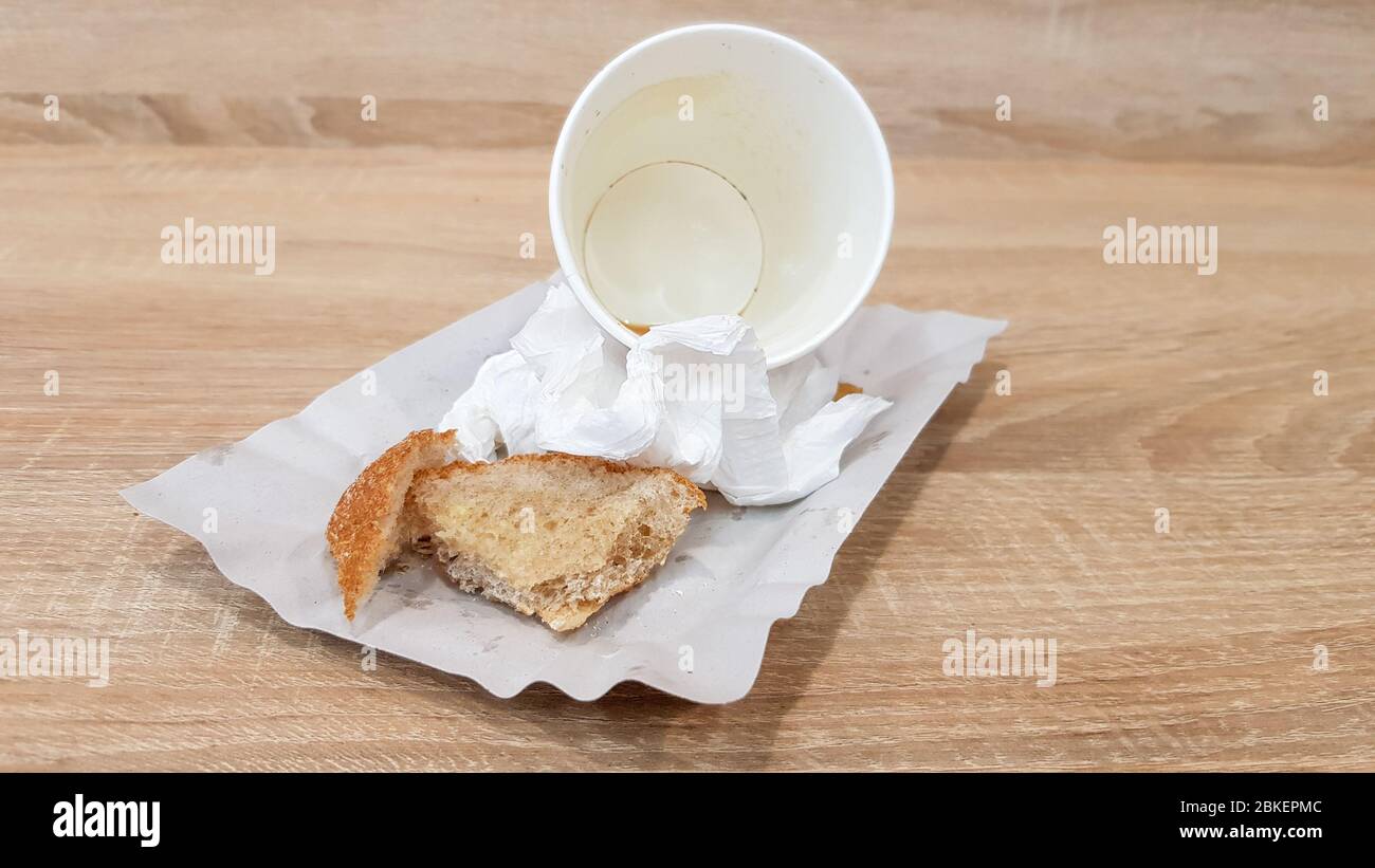 Leftover food on a paper plate and empty dirty paper coffee cup on a ...