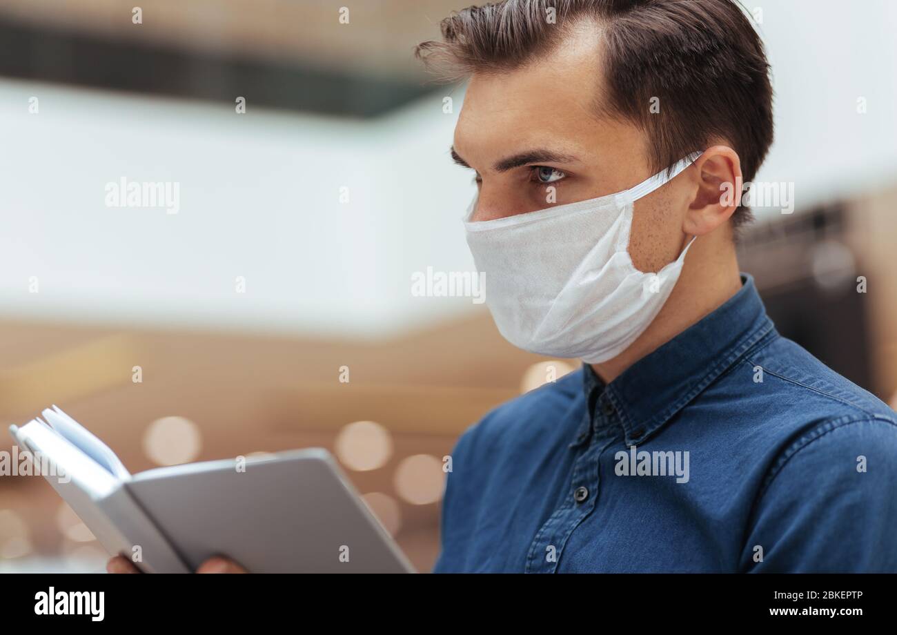 young man reading a book sitting at a table in the food court Stock ...