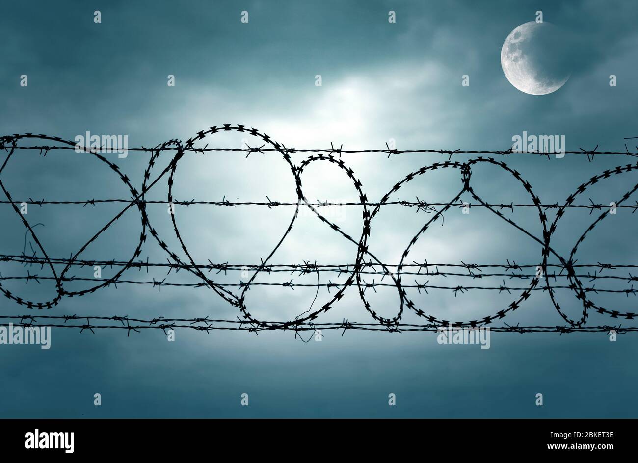 Border with barbed wire of prison during night time with moon, concept ...