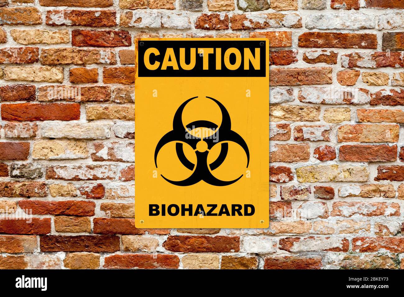 Old yellow warning sign screwed to a brick wall. In the middle of the ...