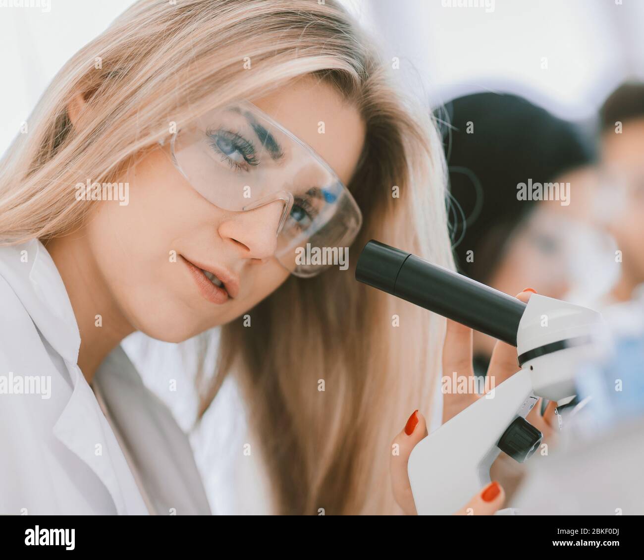 close up.a modern female scientist looks into a microscope in a Stock ...