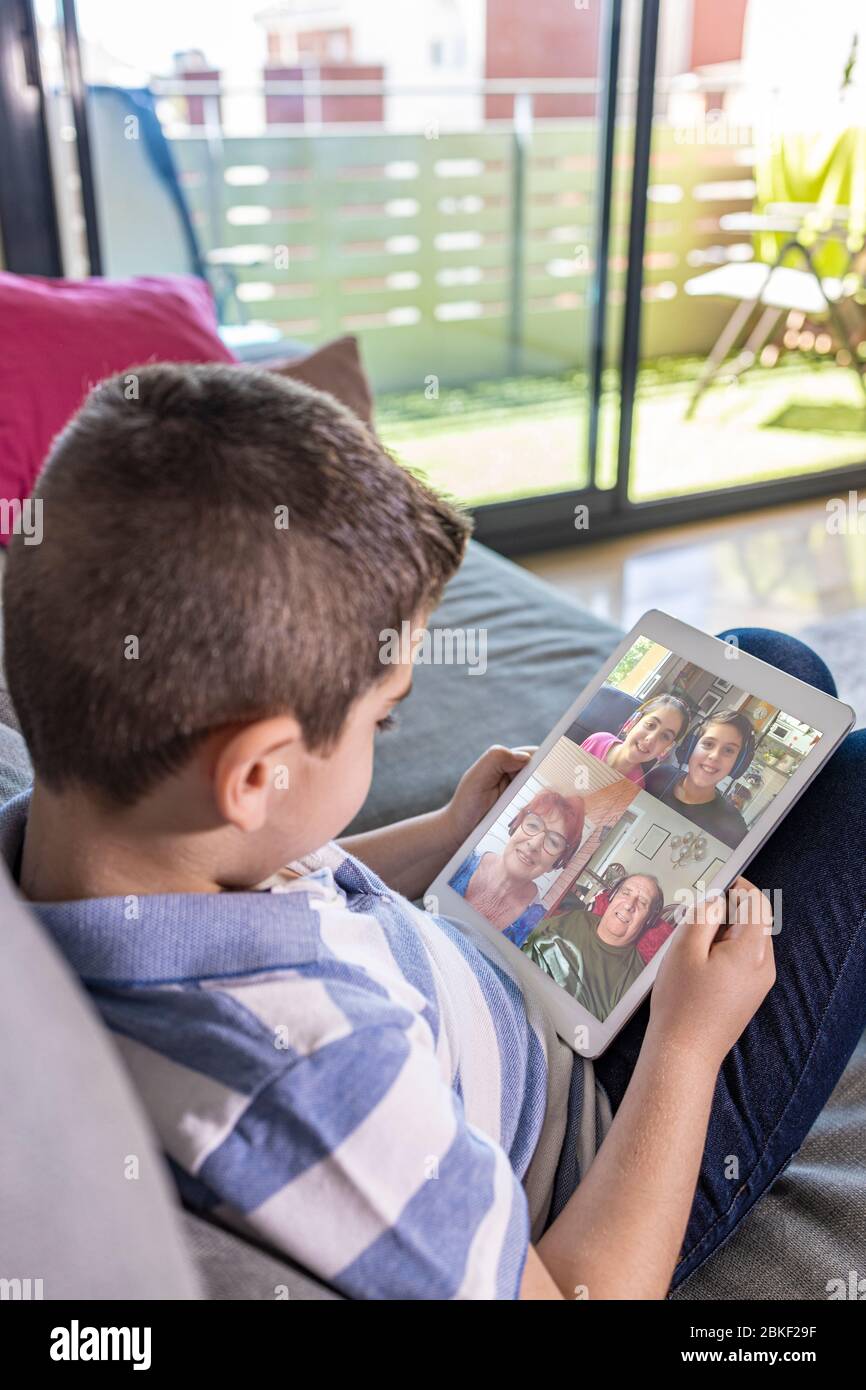 Closeup view of little kid talking with family via video chat at home ...