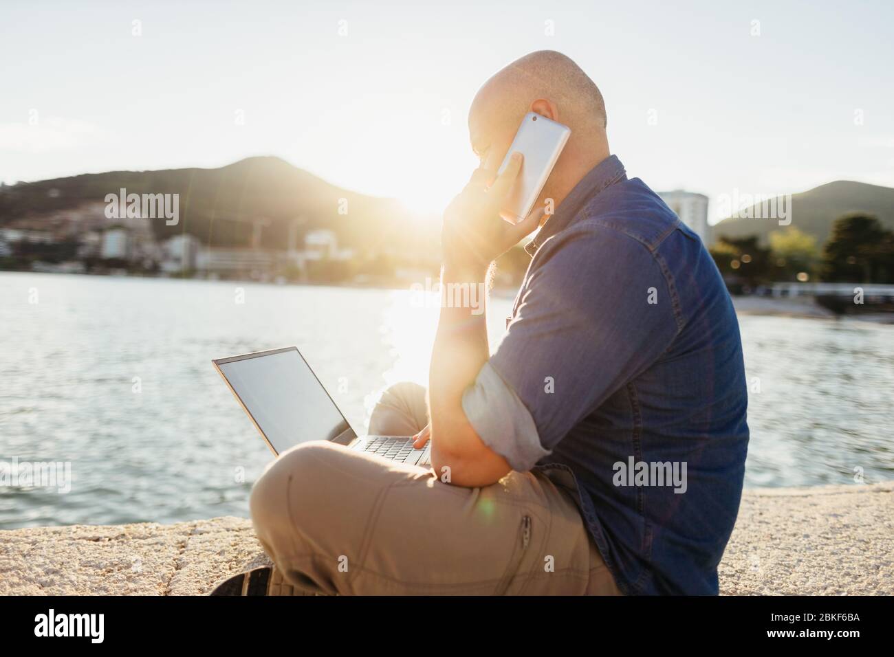 man making online reservation using phone and laptop on beach. man ...