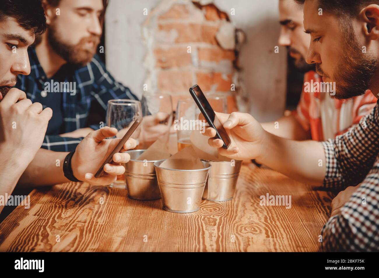 Group friends ignore each other in beer bar, using mobile devices, apps ...