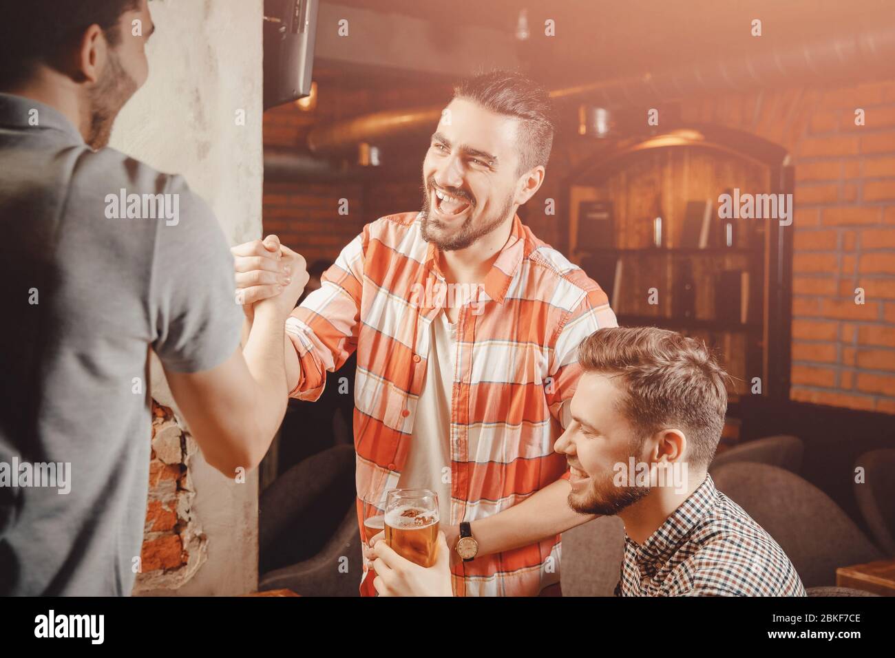 Group men sitting Handshake, drinking beer in pub. friend shaking male ...