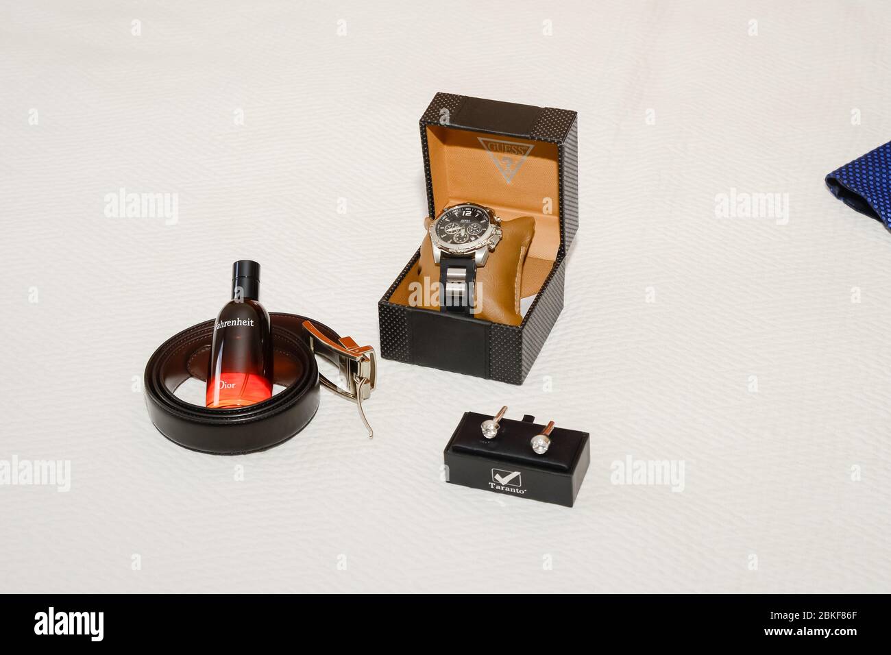Perfume surrounded by a belt and next to a watch and other accessories ...