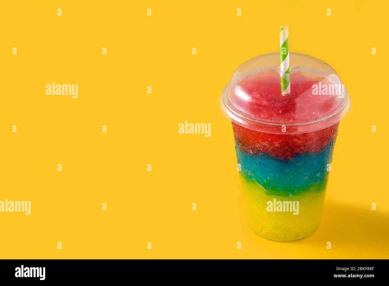 Colorful slushie of differents flavors with straw on yellow background ...
