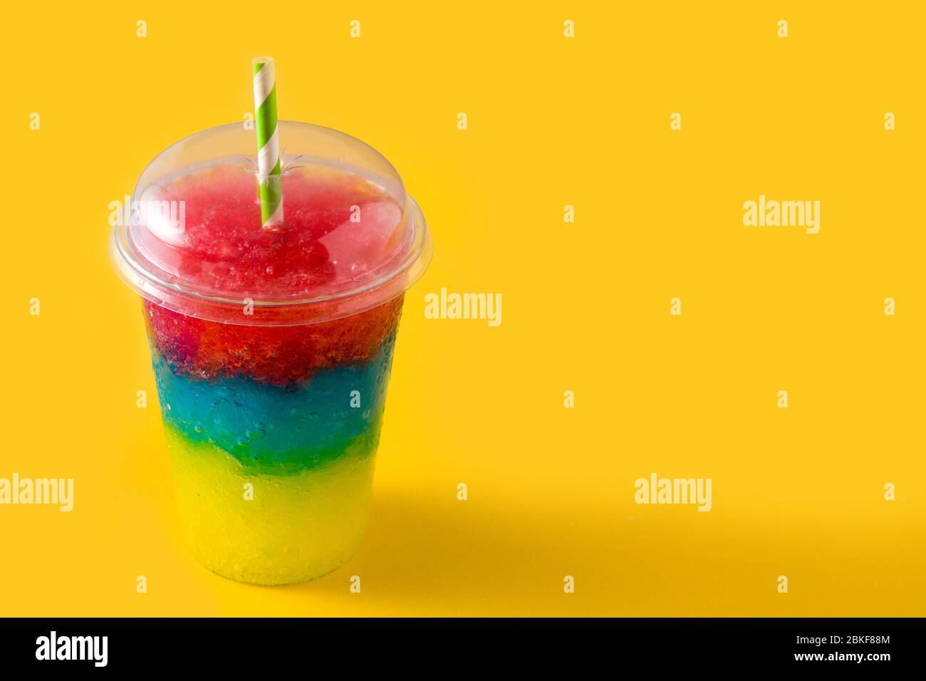 Colorful slushie of differents flavors with straw on yellow background ...