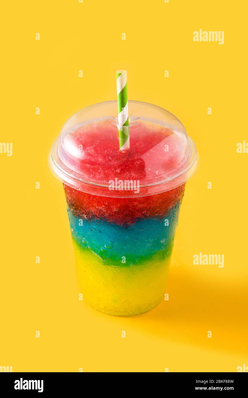 Colorful slushie of differents flavors with straw on yellow background ...
