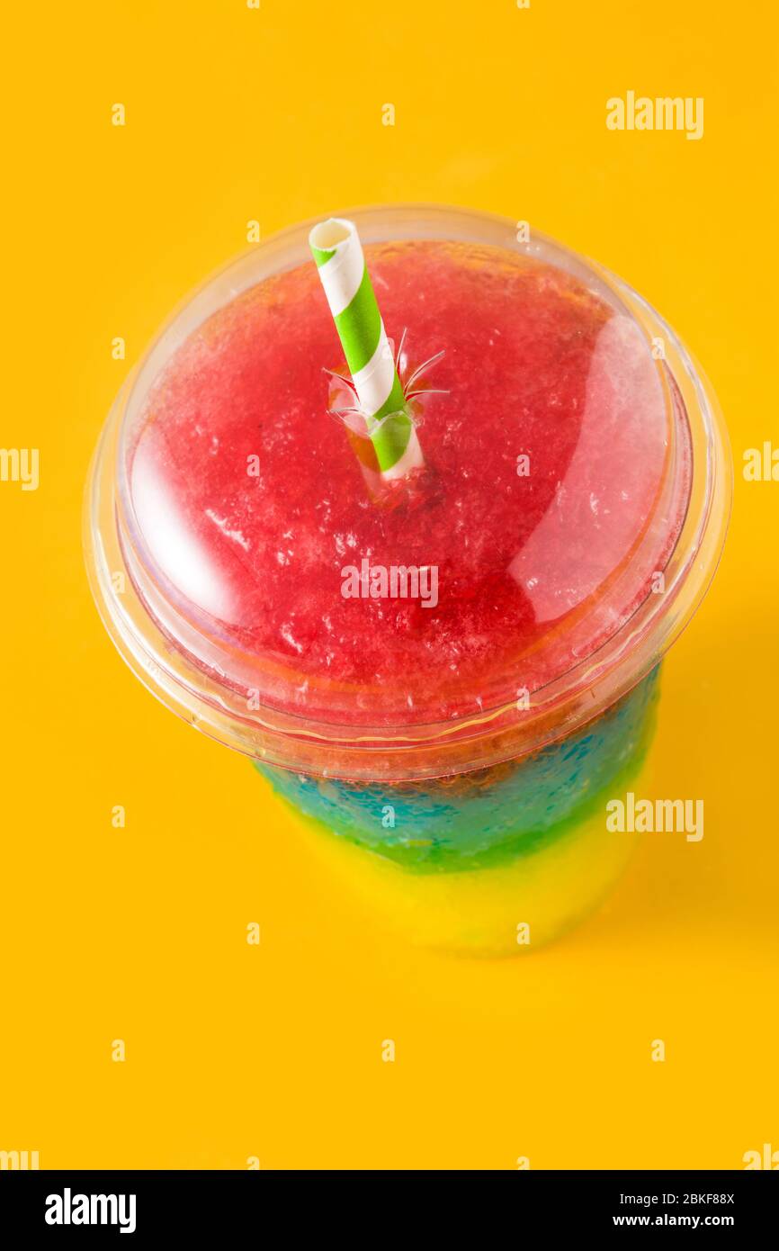Colorful slushie of differents flavors with straw on yellow background ...
