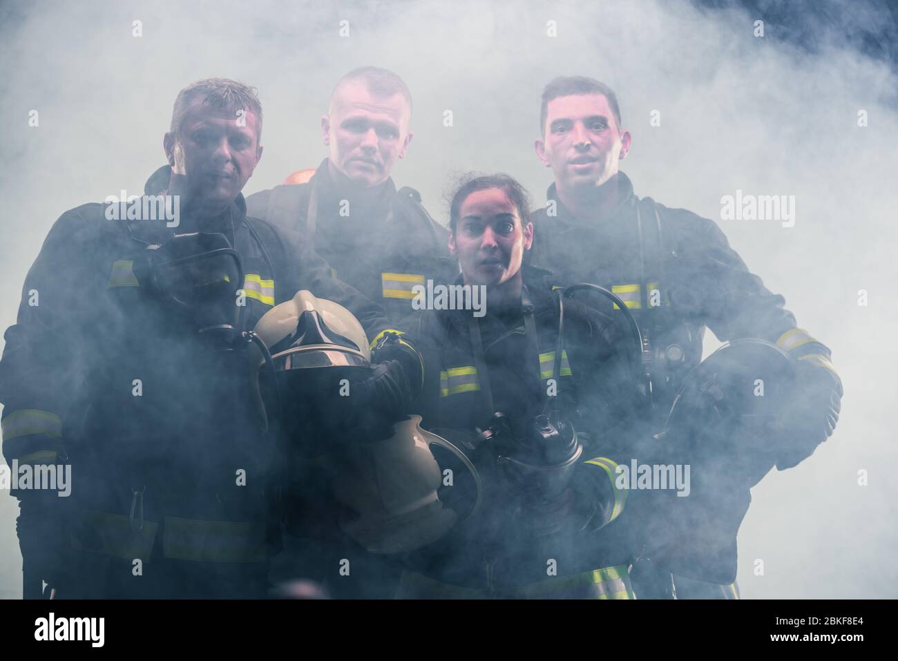 Team of firefighters standing the middle of the fire extinguisher's ...