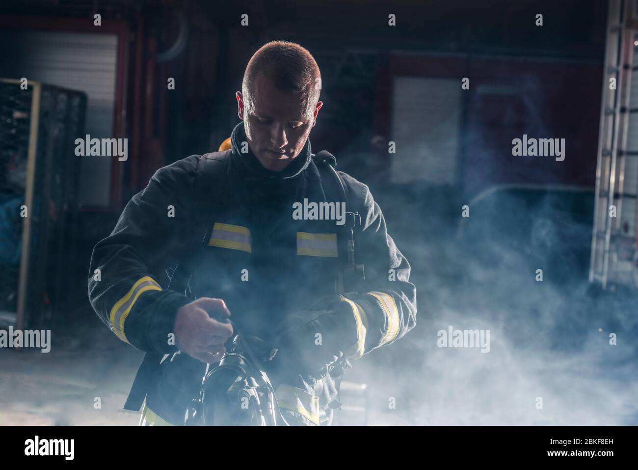 Portrait of a fireman wearing firefighter turnouts and helmet. Dark ...