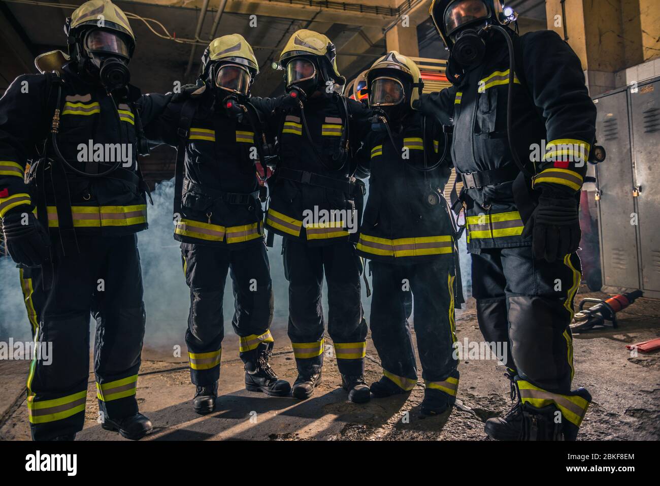 Team of firemen in uniform with gas masks inside the fire department ...