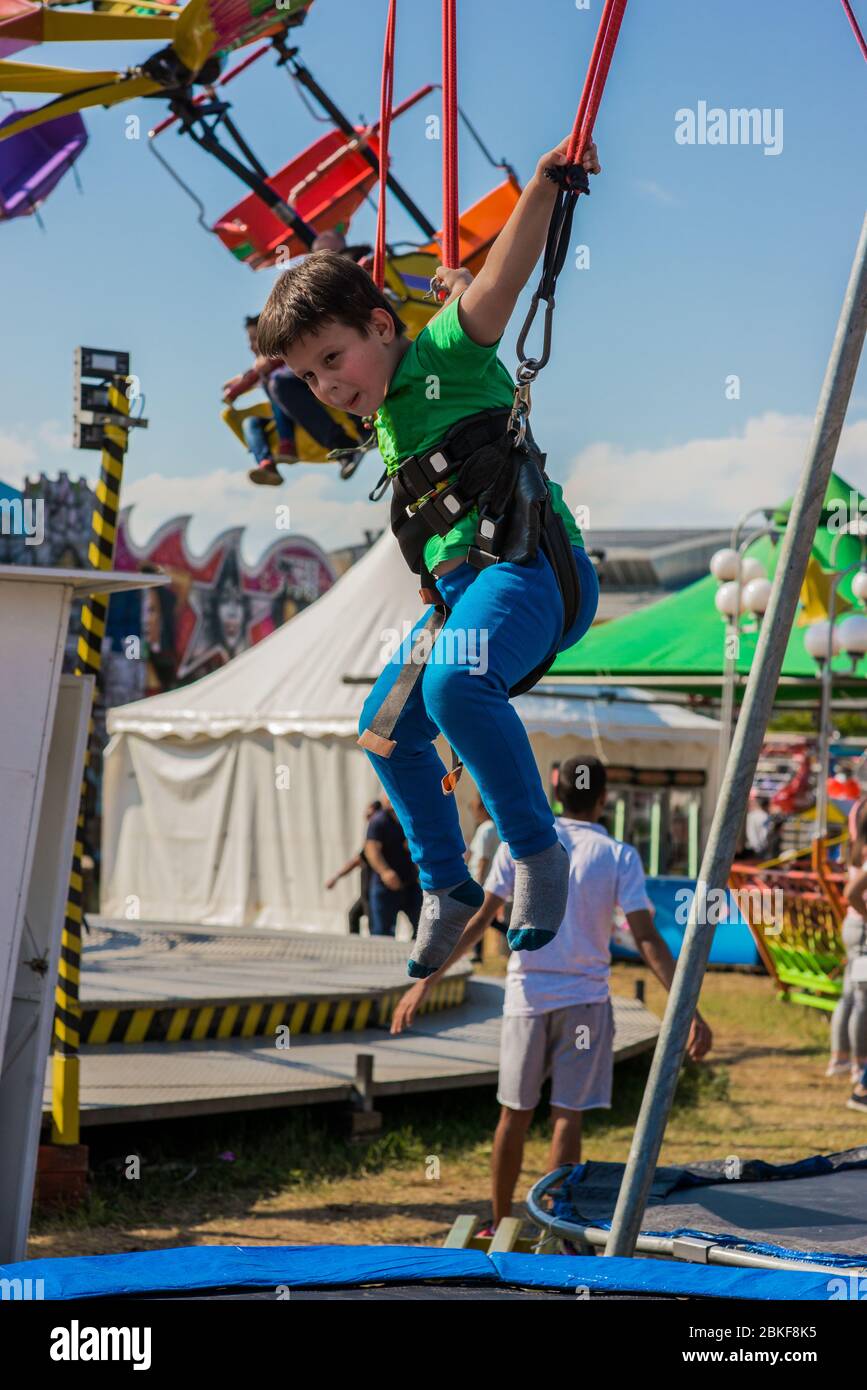 Smiling cheerful boy jumping on the trampoline at a local carnival ...