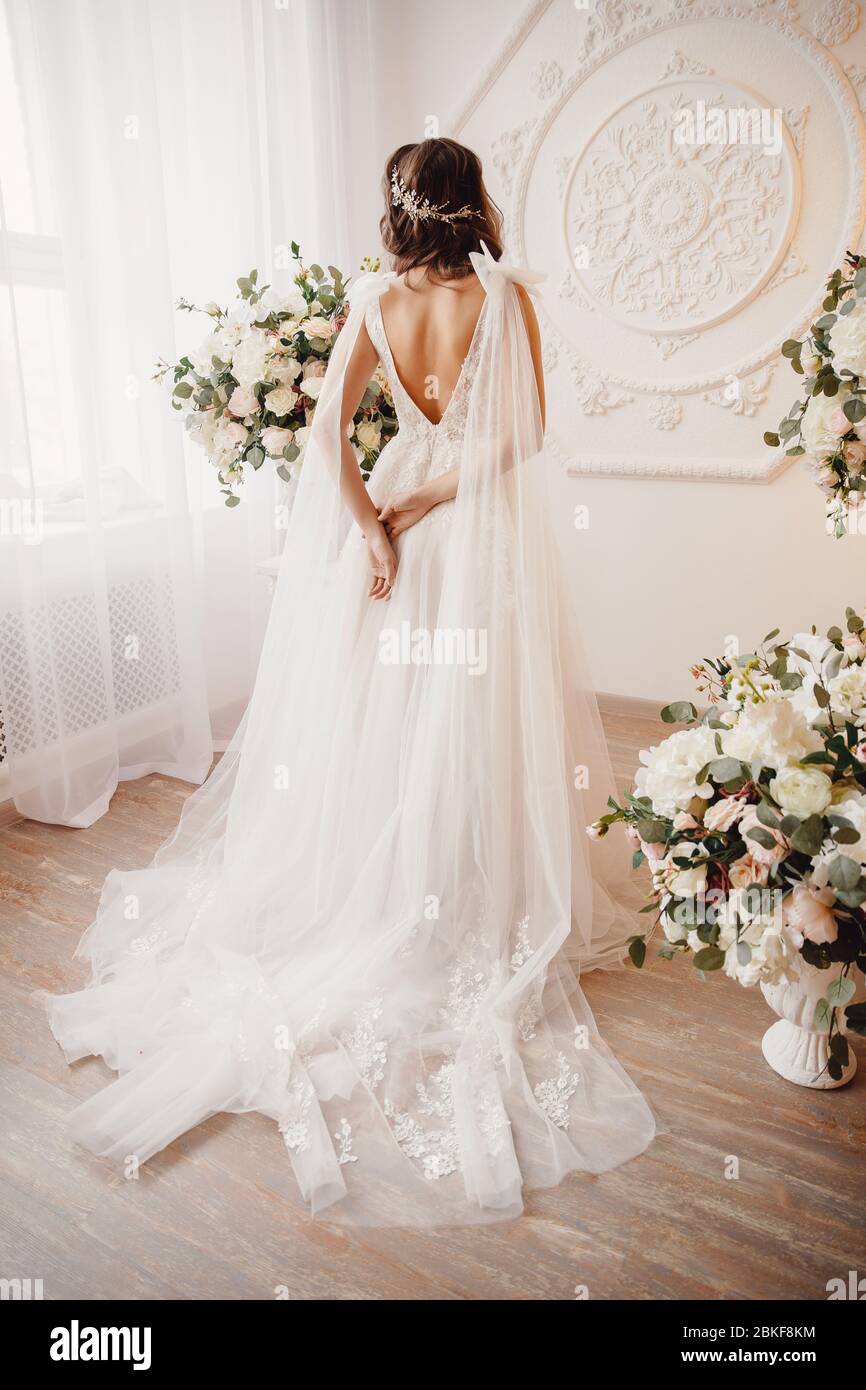 Photo from back Beautiful young woman in white wedding dress smiling ...