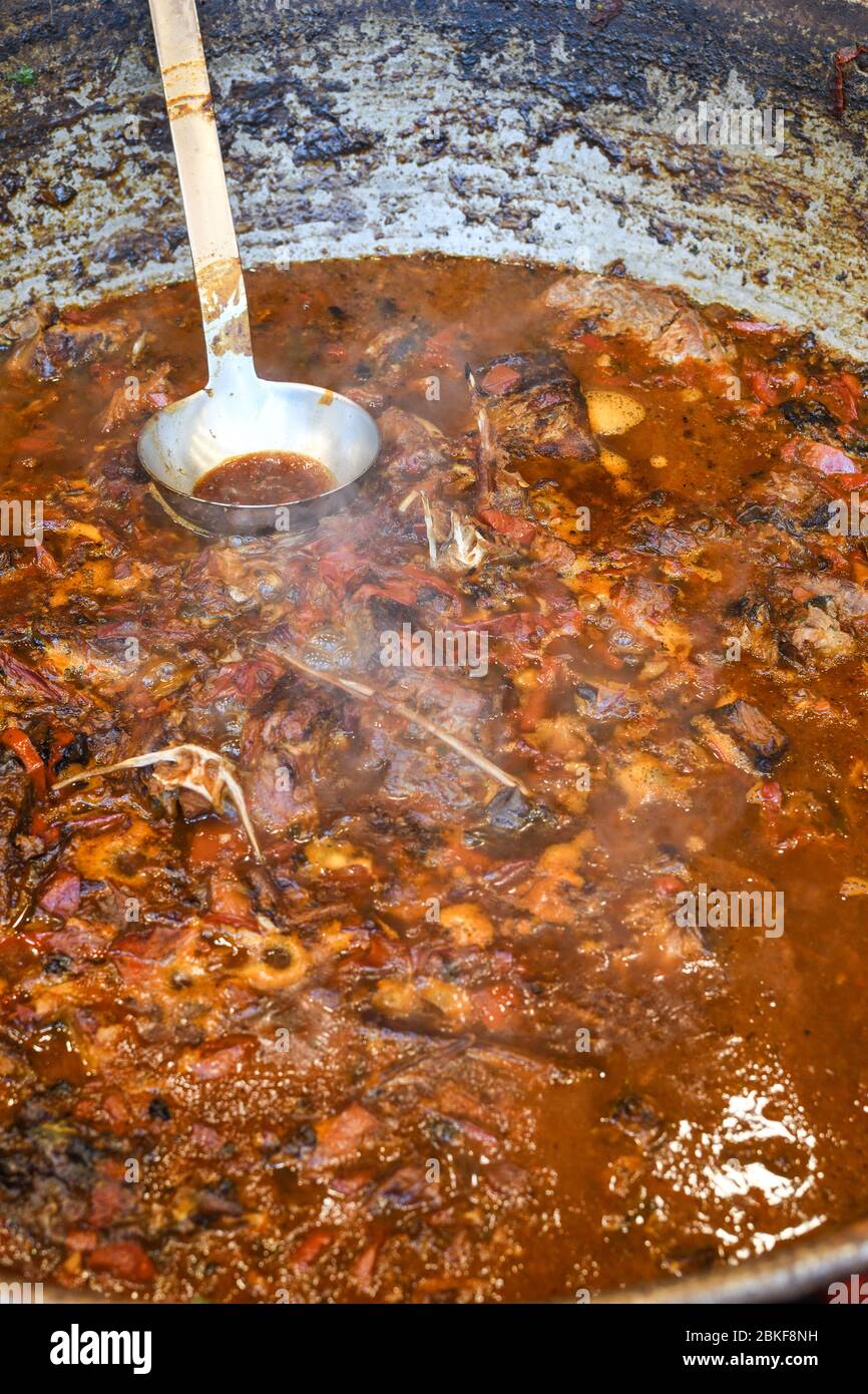 Traditional fish stew being prepared in a rustic bowl over a wood ...