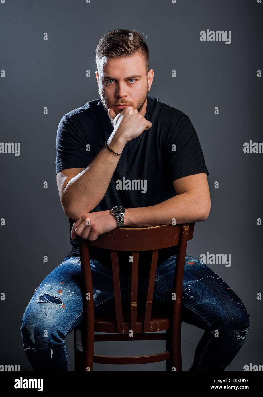 Trendy modern young man dressed in trendy denim jeans and black top ...