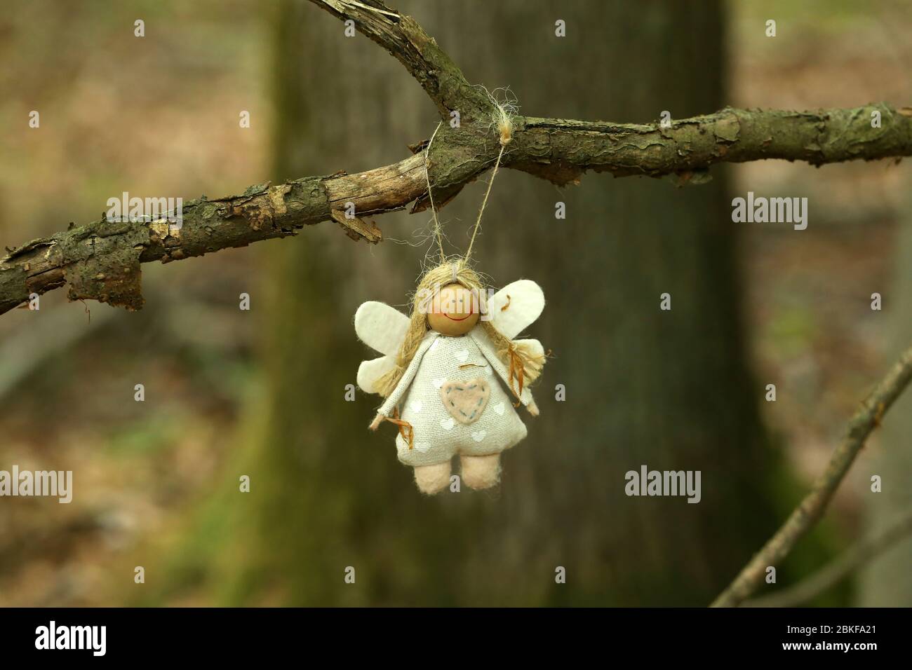 Figurine of a funny little angel hanging on a tree in the forest Stock ...