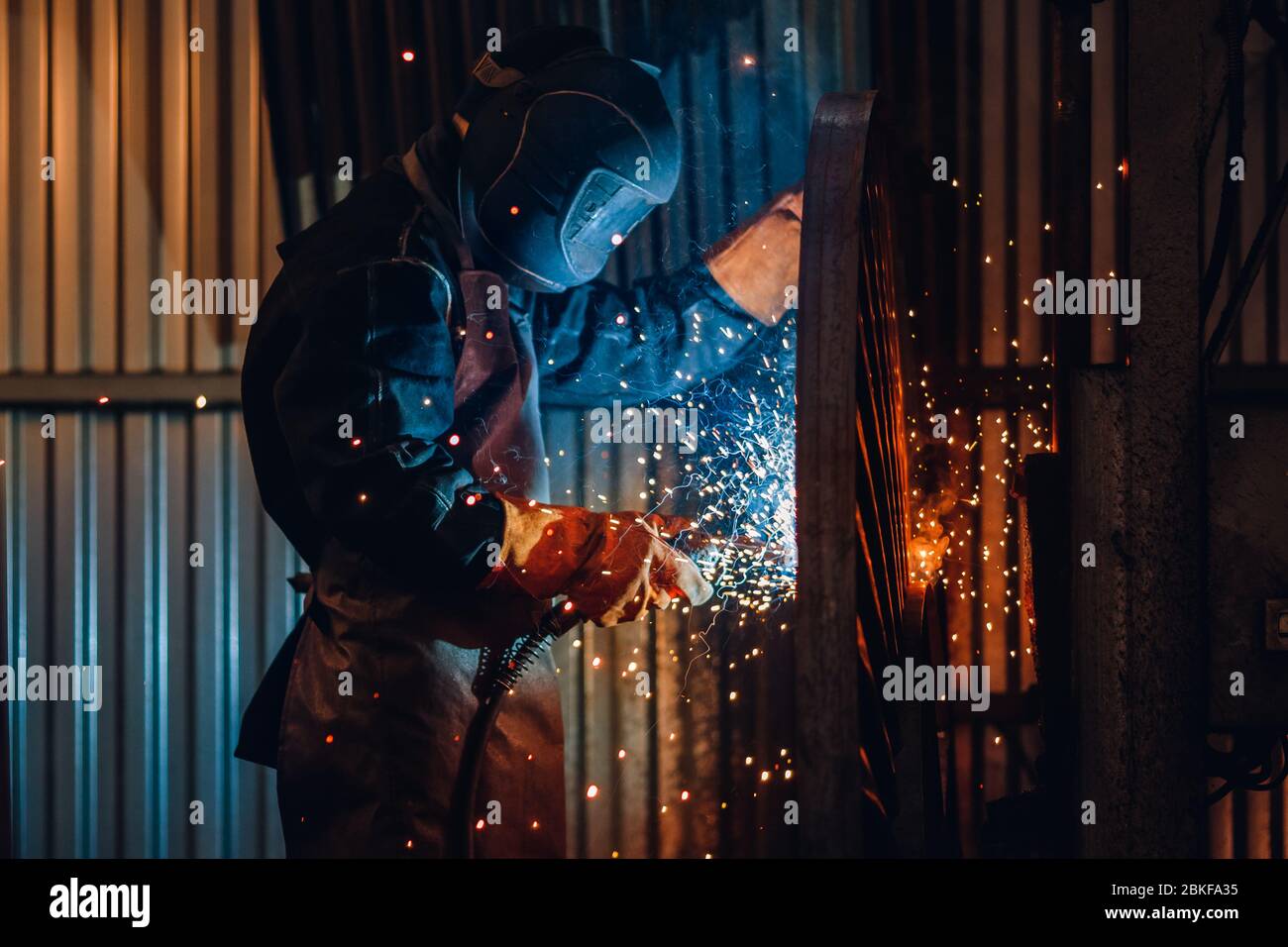 Professional welder performs welding work on metal in protective mask ...