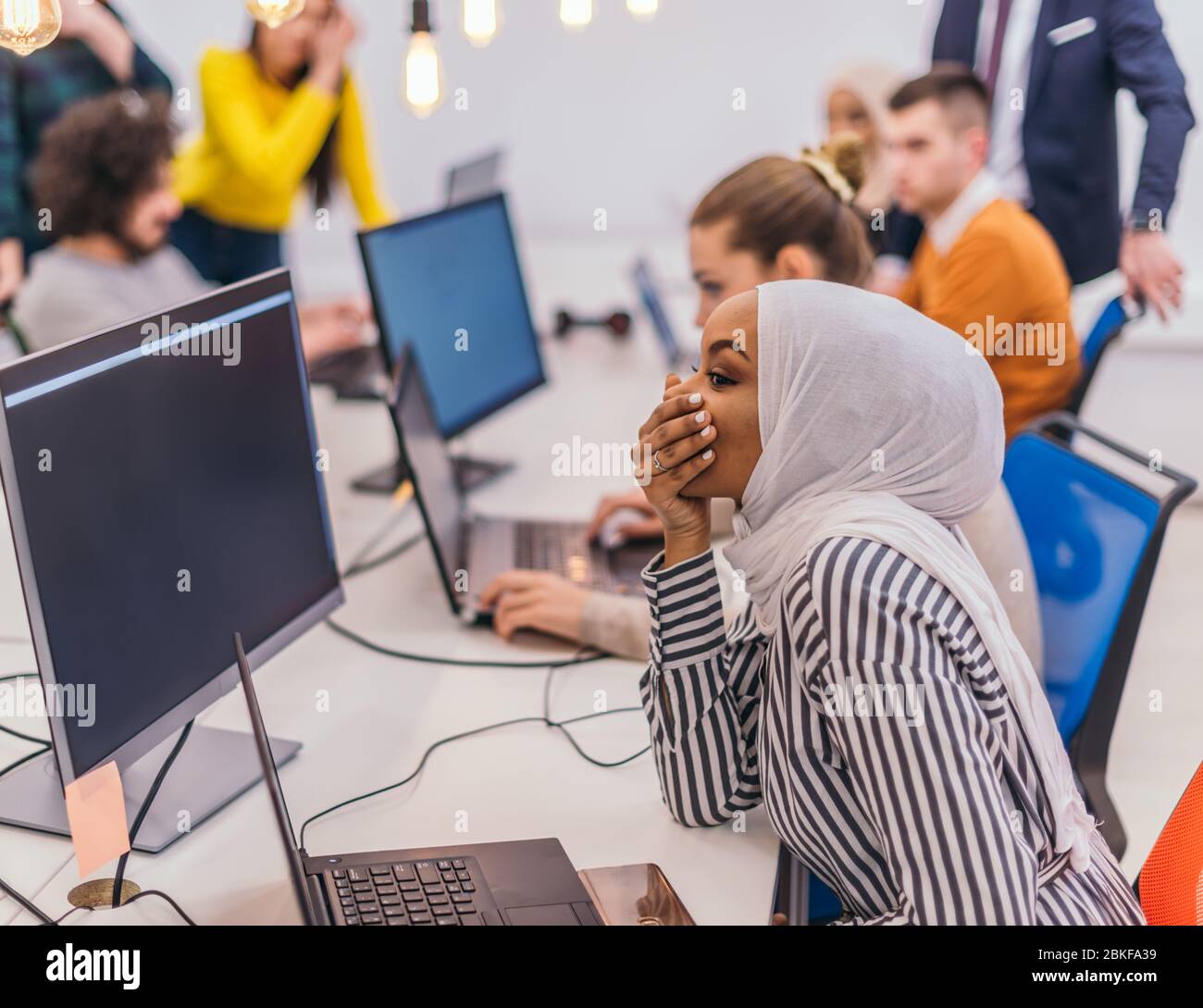Surprised african muslim woman working in bright coworking space on ...