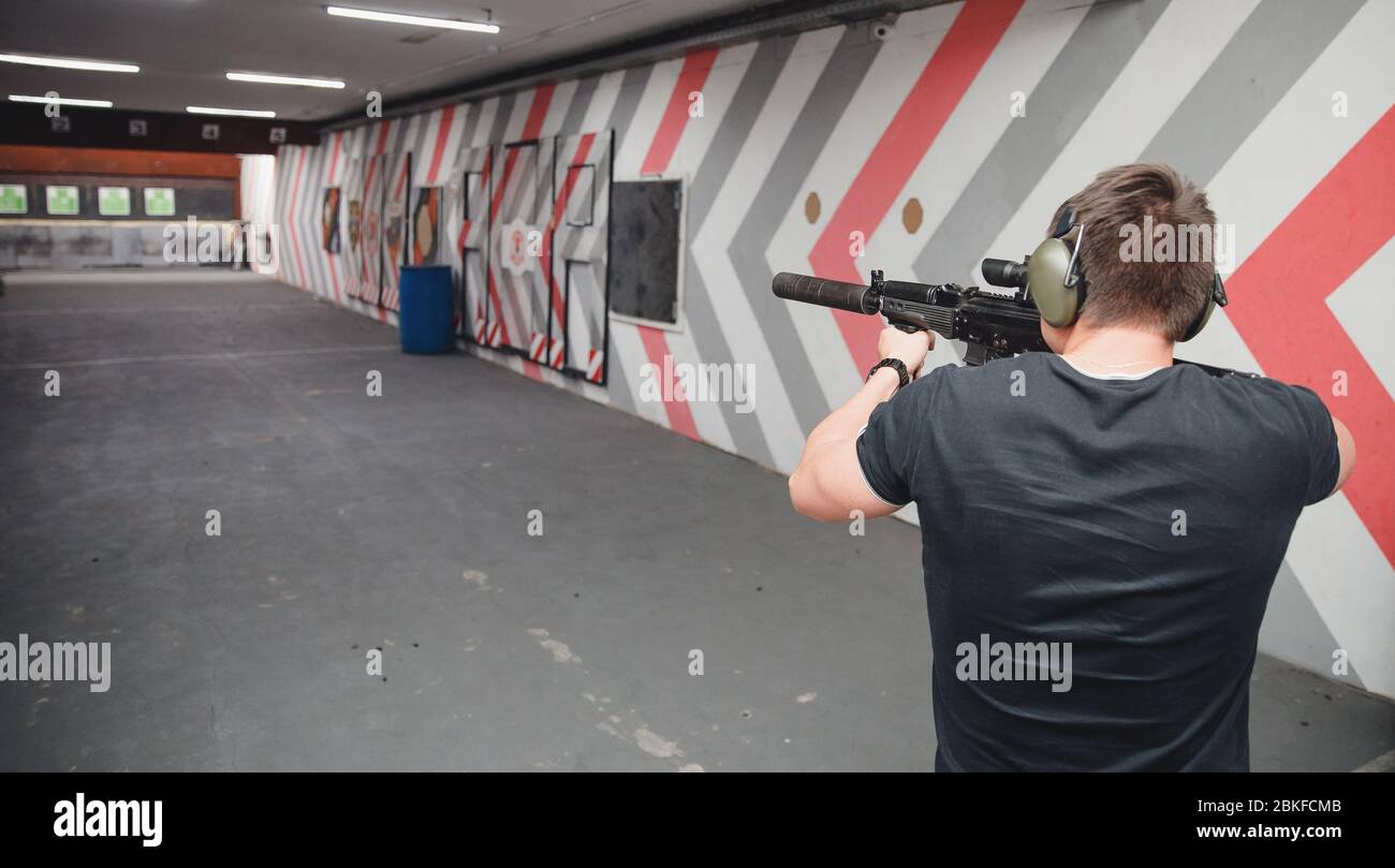 Shooting training. Man shoots from aim gun in paper target Stock Photo ...