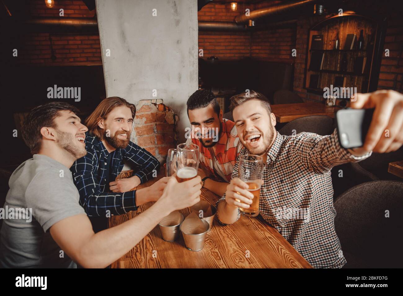 Four young bearded men in casual clothes smiling, taking selfie and ...