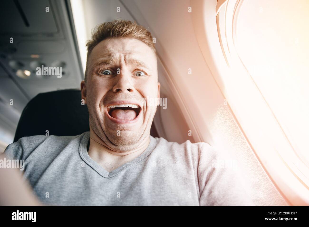 Male passenger in plane screams and cries, aerophobia. background of ...
