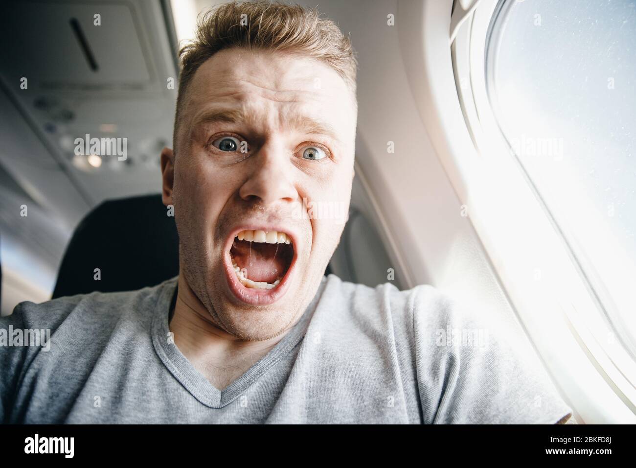 Male passenger in plane screams and cries, aerophobia. background of ...