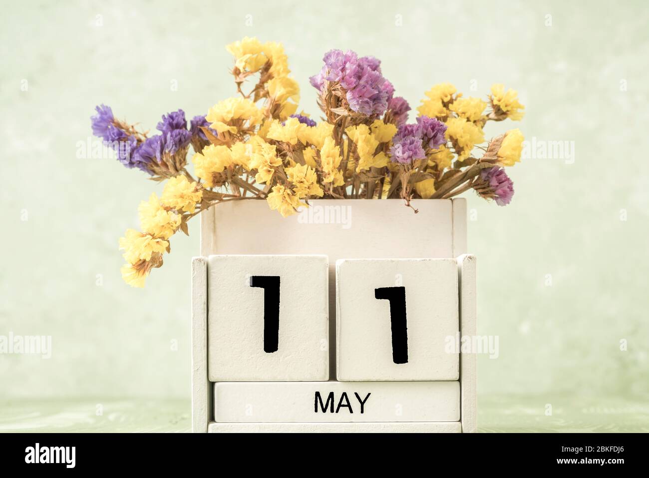 White cube calendar for may decorated with flowers over green ...