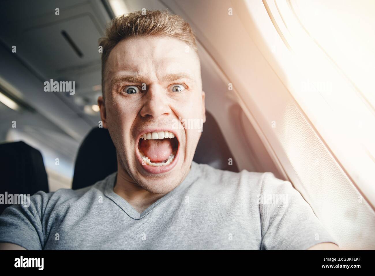 Male passenger in plane screams and cries, aerophobia. background of ...