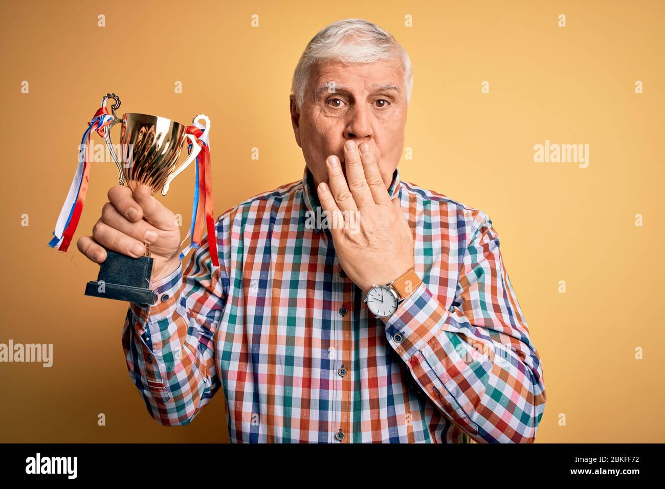 Senior handsome hoary champion man holding trophy award for victory ...
