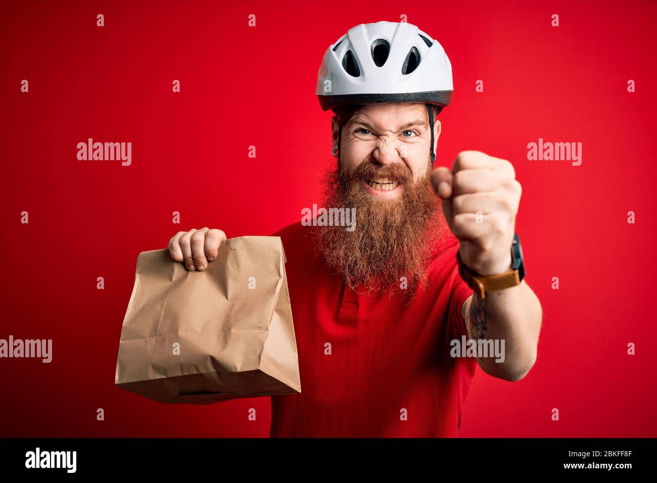 Redhead Irish delivery man with beard wearing bike helmet and holding ...