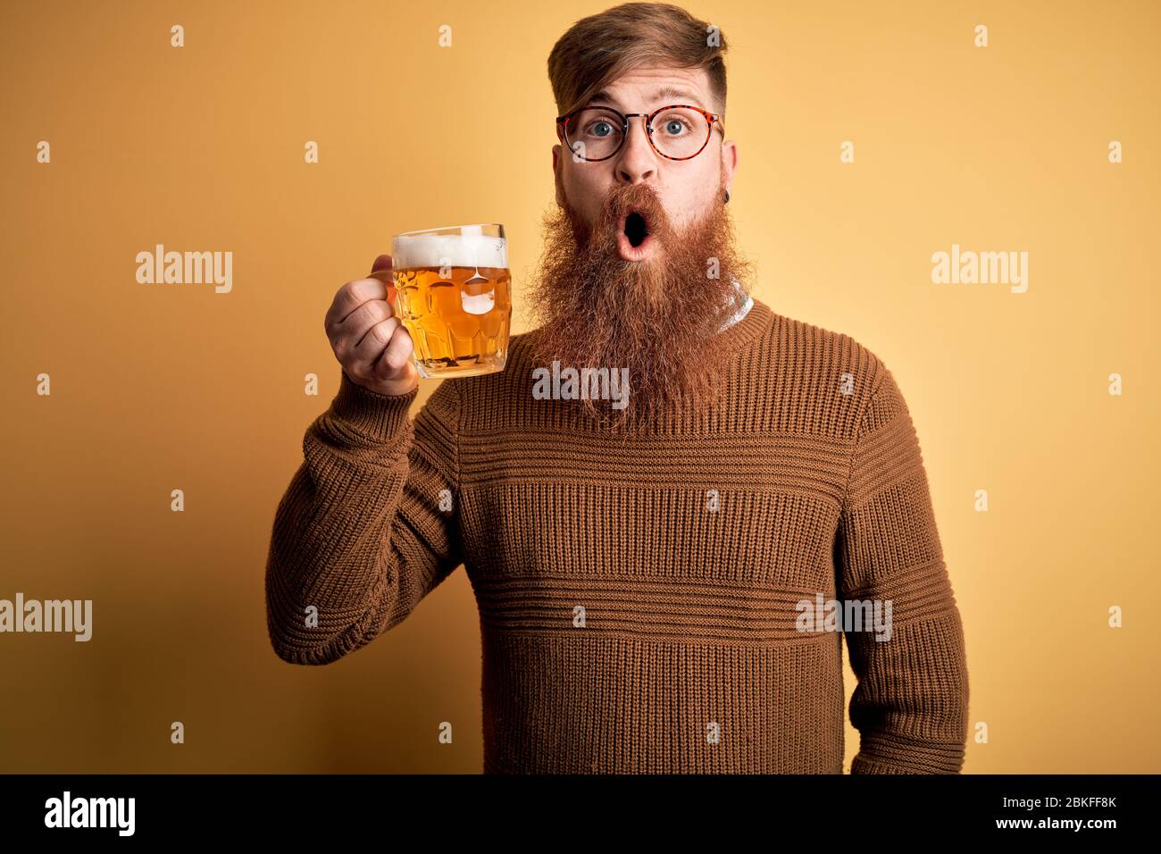 Irish redhead man with beard drinking a glass of refreshing beer over ...