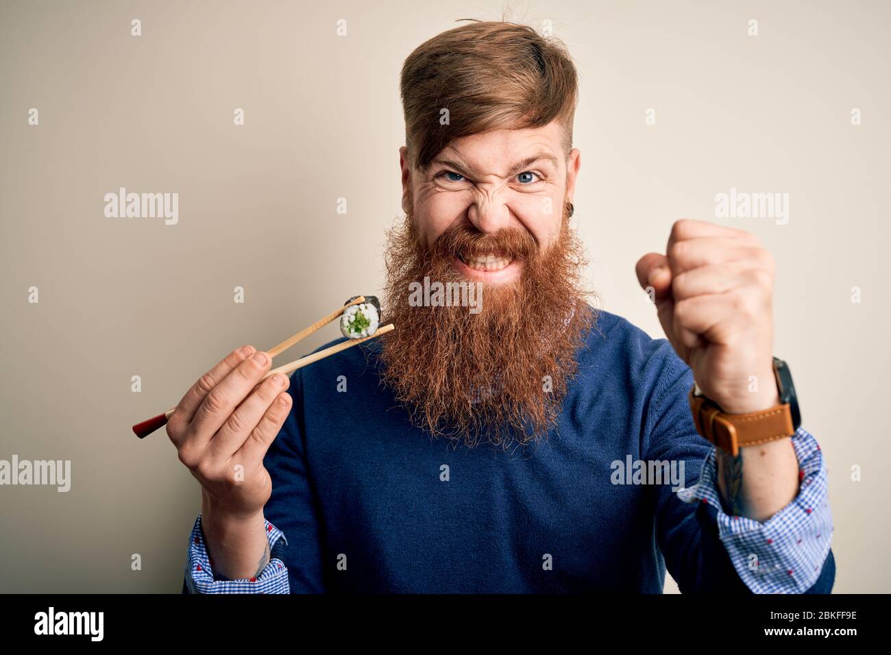 Redhead Irish man with beard eating green maki sushi using chopsticks ...