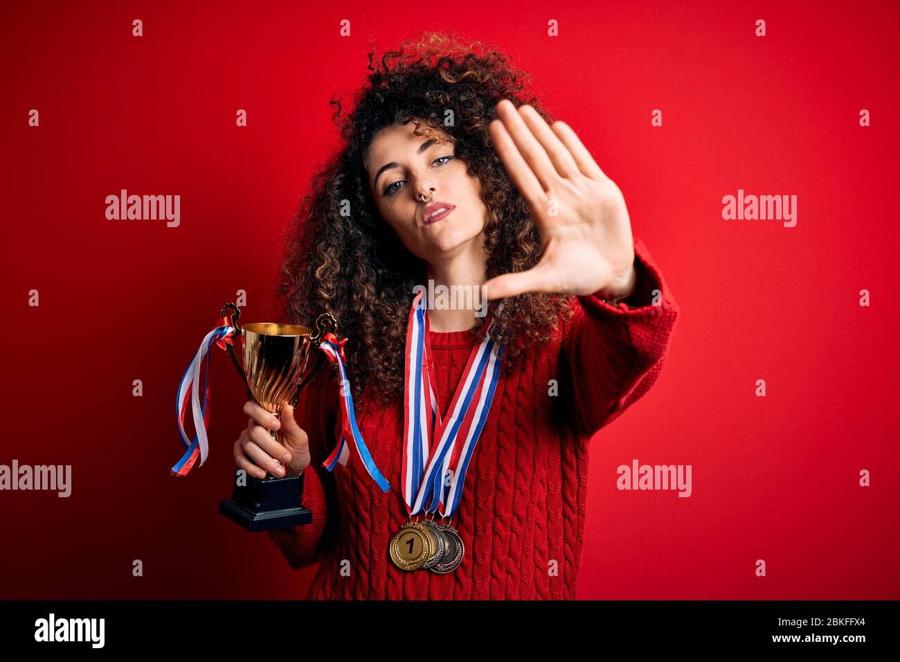 Young beautiful successful woman with curly hair and piercing holding ...