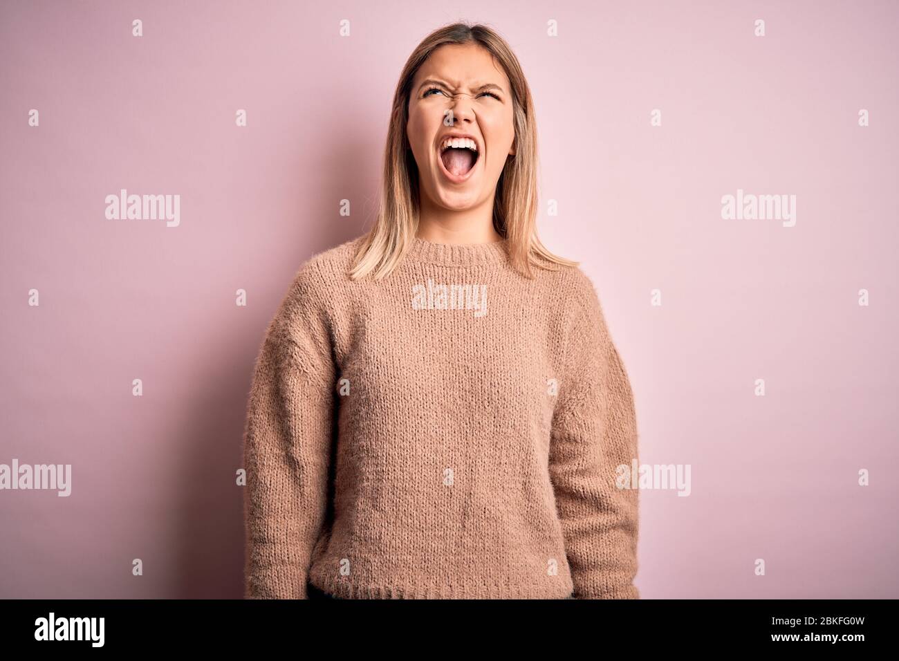 Young beautiful blonde woman wearing winter wool sweater over pink ...