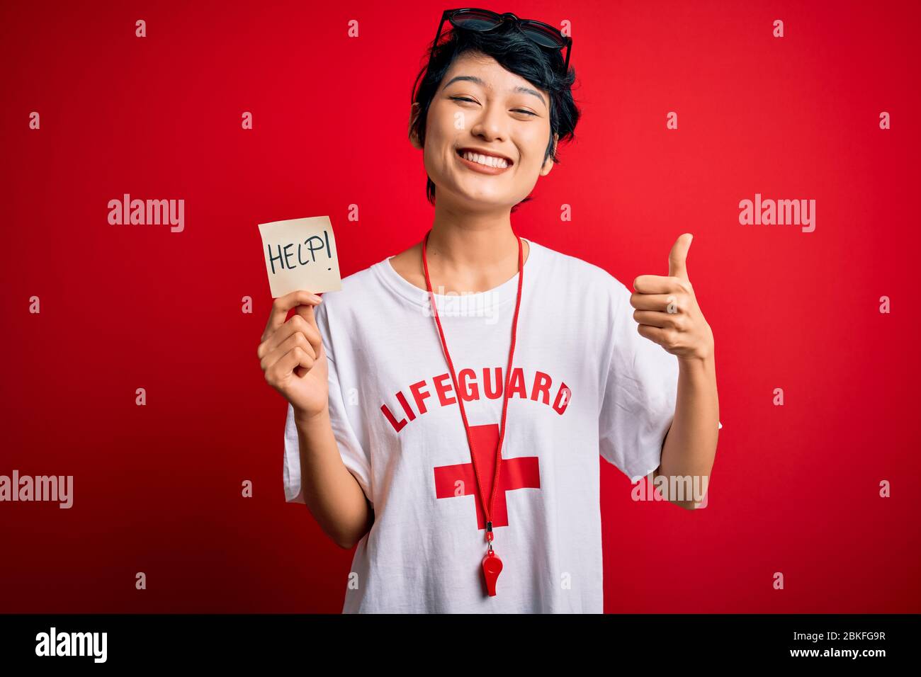 Young beautiful asian lifeguard girl using whistle holding reminder ...