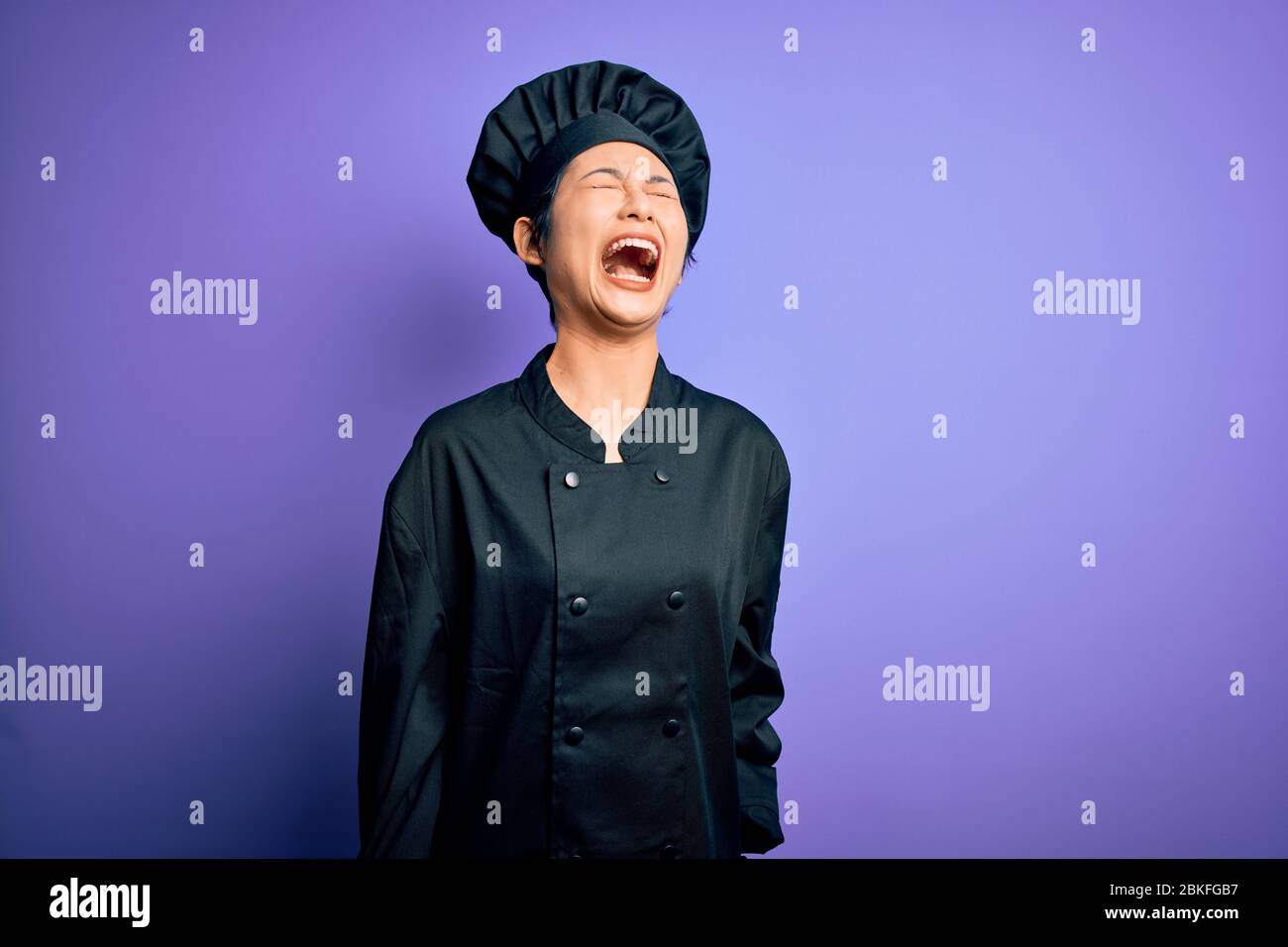 Young beautiful chinese chef woman wearing cooker uniform and hat over ...