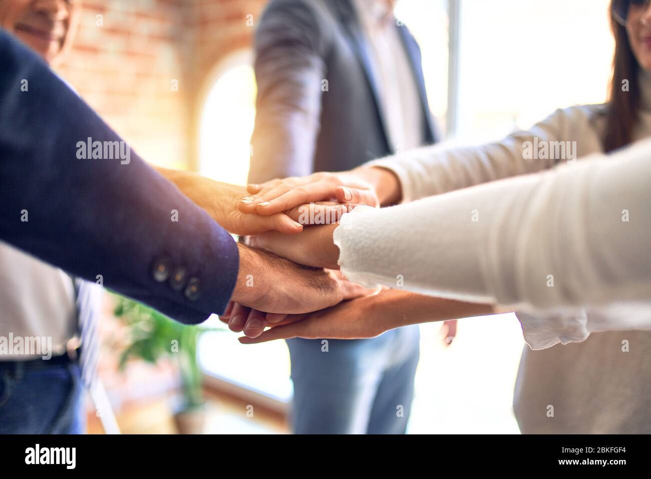 Group of business workers standing with hands together at the office ...