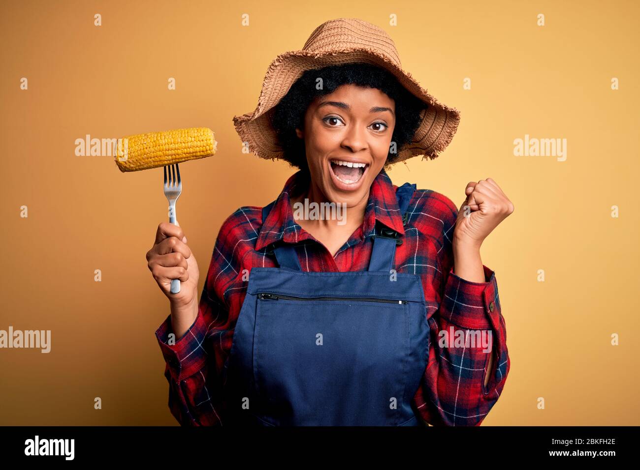 Young African American afro farmer woman with curly hair wearing apron ...