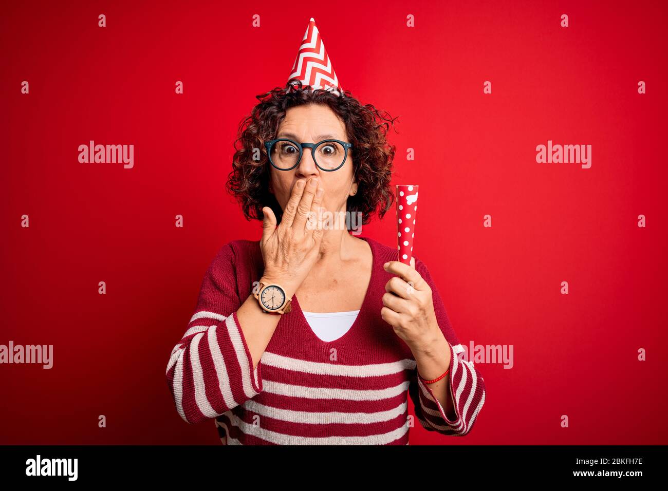 Middle age curly hair woman wearing birthday funny hat holding party ...