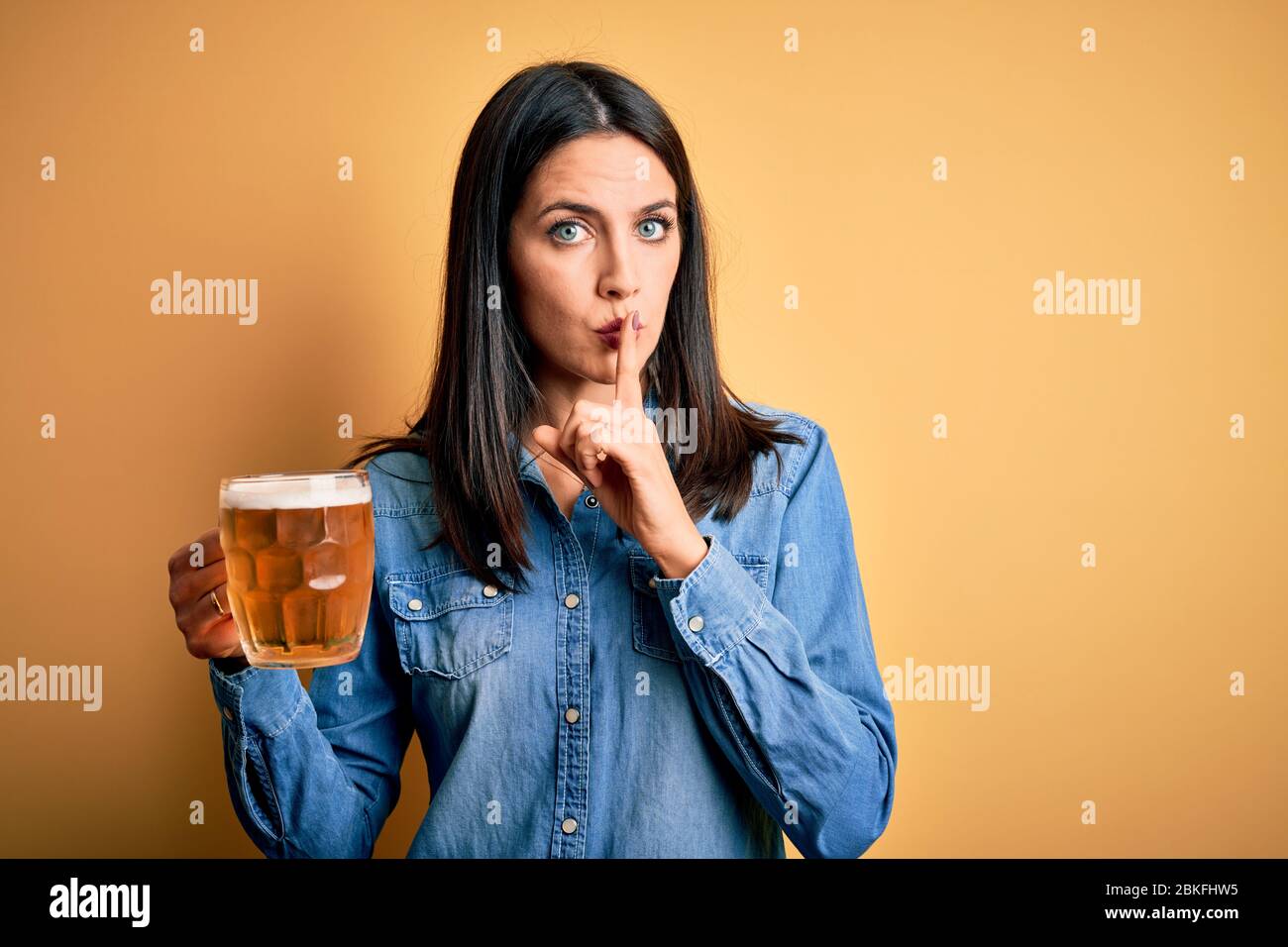 Young woman with blue eyes drinking jar of beer standing over isolated ...