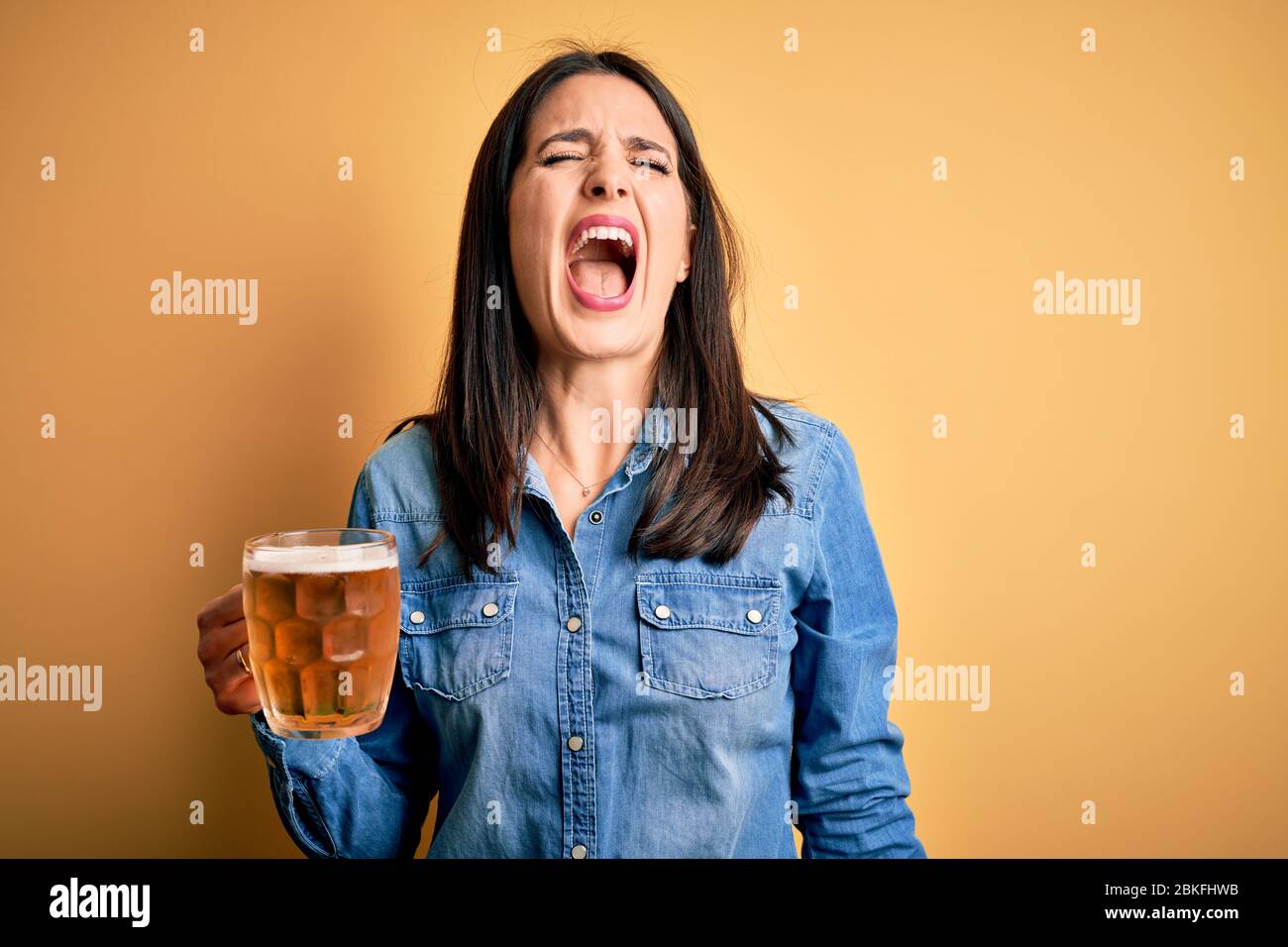 Young woman with blue eyes drinking jar of beer standing over isolated ...