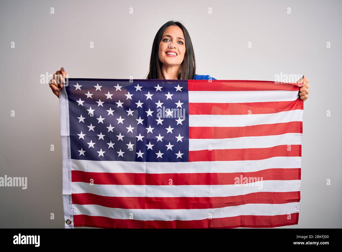 Young beautiful brunette patriotic woman with blue eyes smiling happy ...