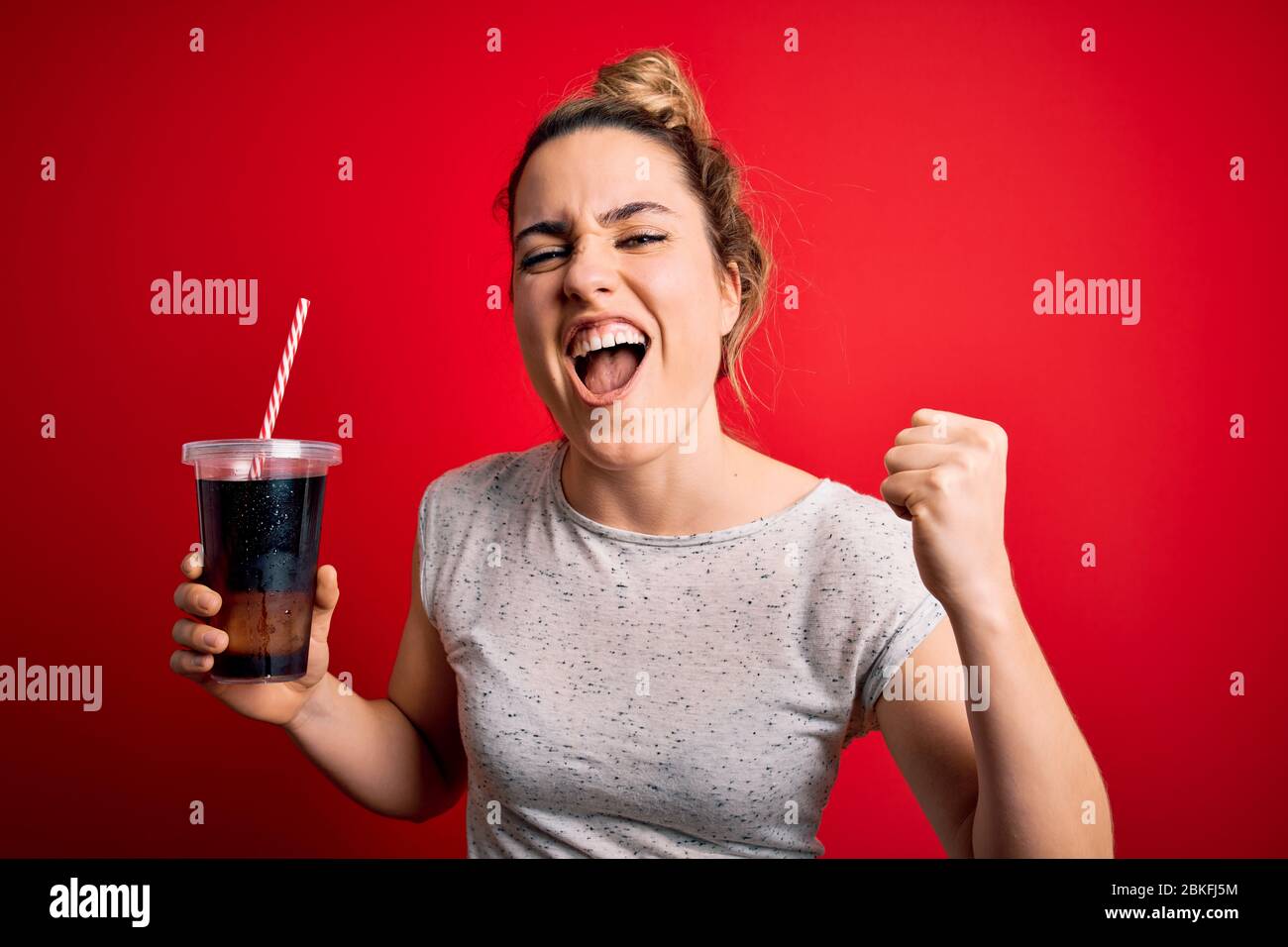 Beautiful blonde woman drinking cola fizzy beverage to refreshment over ...
