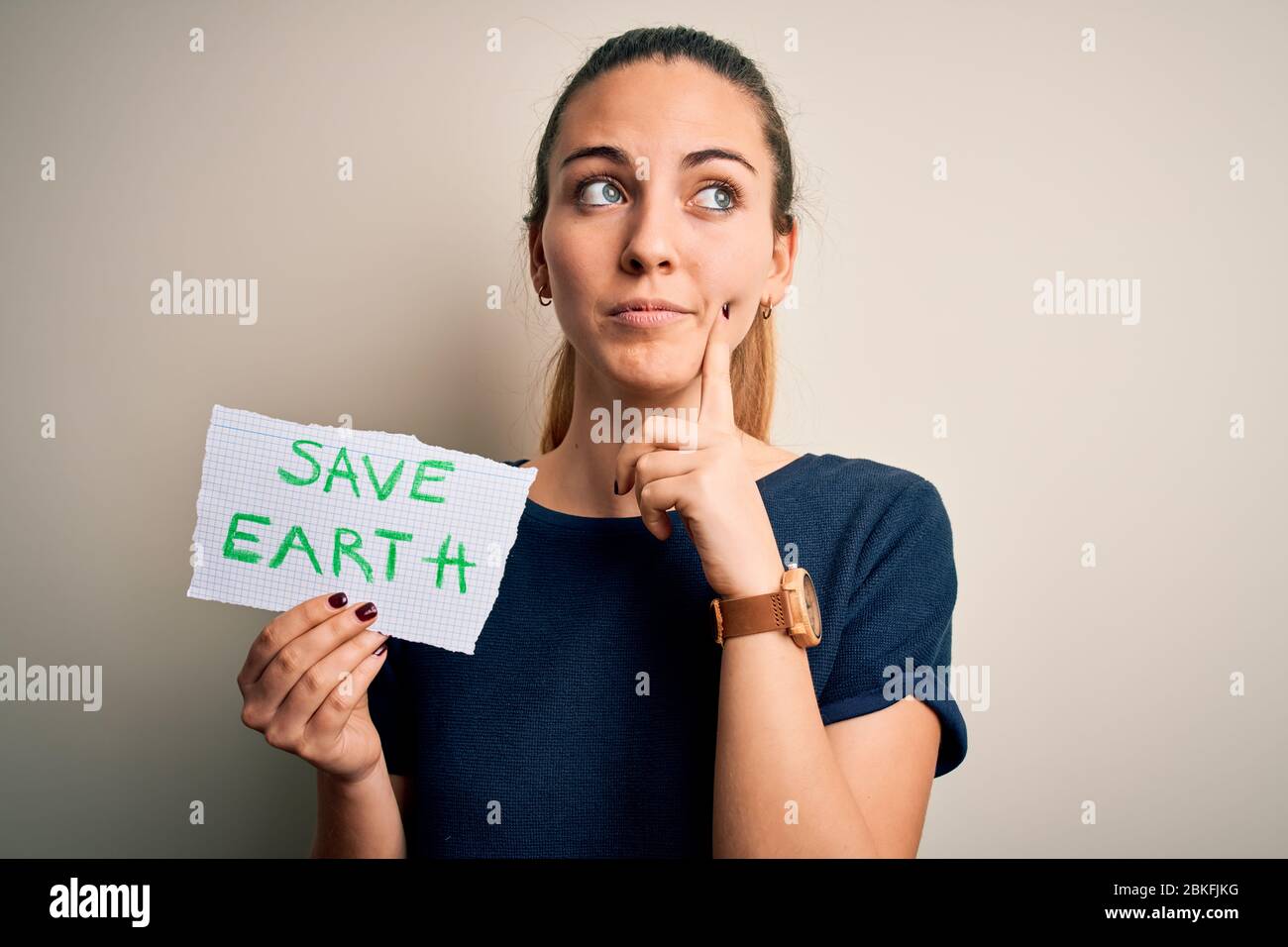 Young beautiful woman holding paper asking for save earth and enviroment conservation serious ...