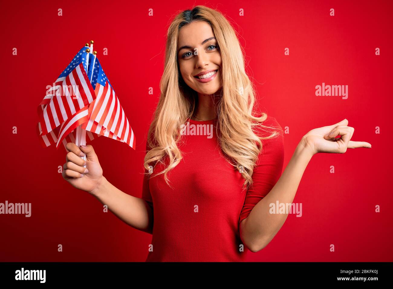 Beautiful blonde patriotic woman holding united states flags ...