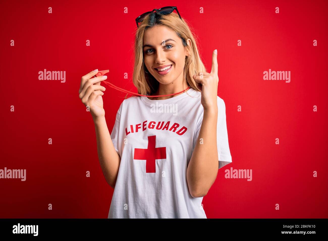Young beautiful blonde lifeguard woman wearing t-shirt with red cross ...