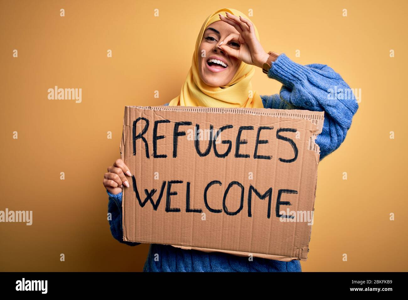 Beautiful arab woman wearing islamic hijab holding banner with refugees ...